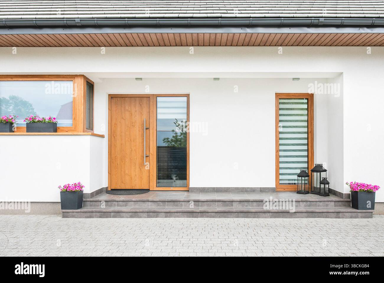 A front door detail with a stone accent wall, a brown door, covered ...
