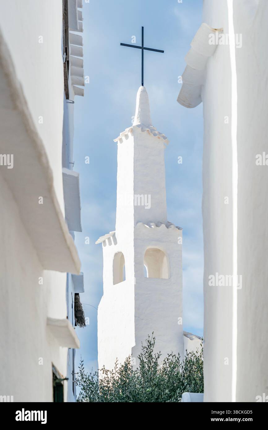 Traditional whitewashed church tower with a simple cross in a narrow ...