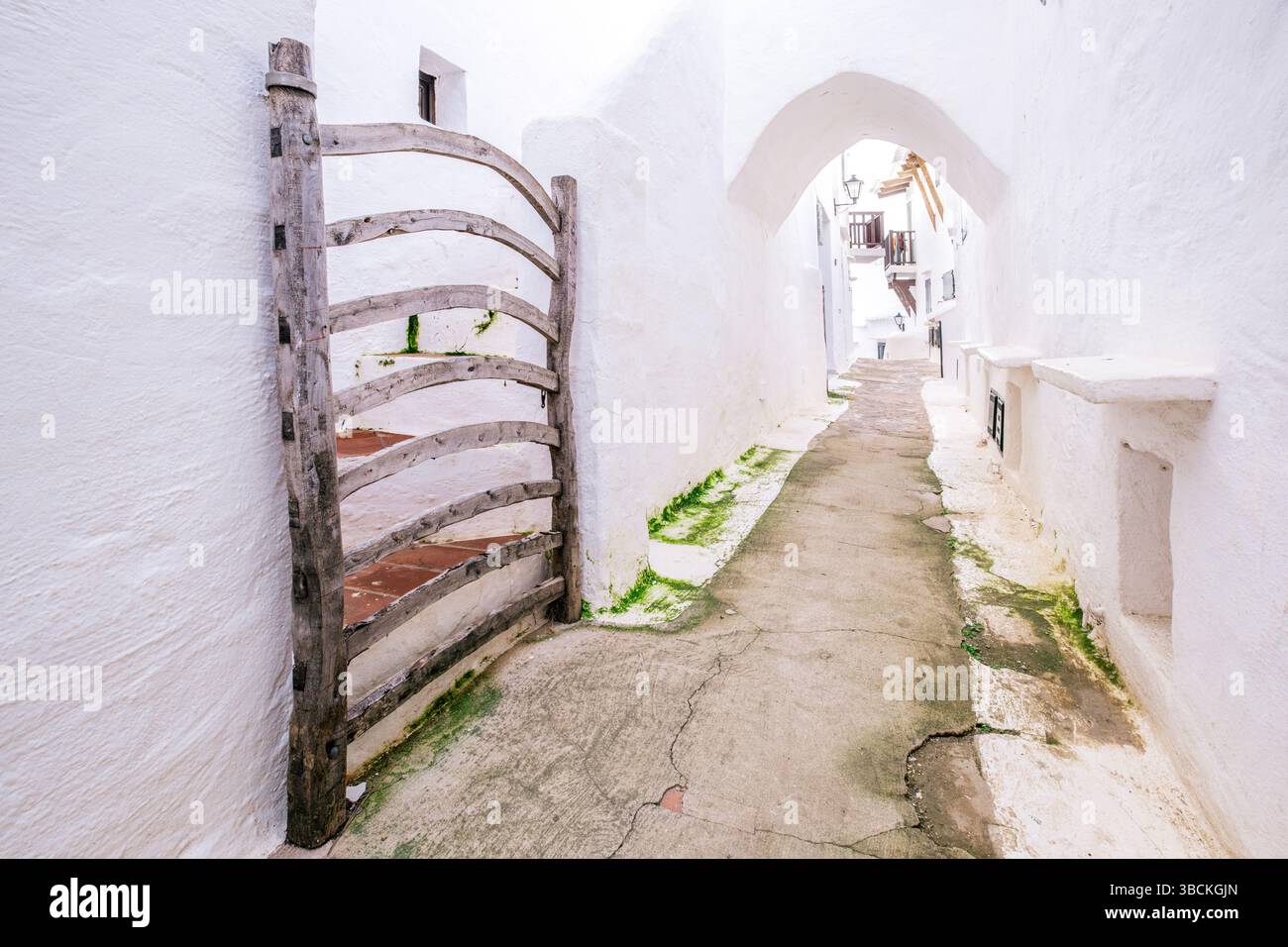 Narrow street with traditional Menorcan wooden gate in Binibeca Vell ...