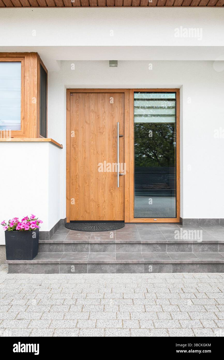 A front door detail with a stone accent wall, a brown door, covered ...