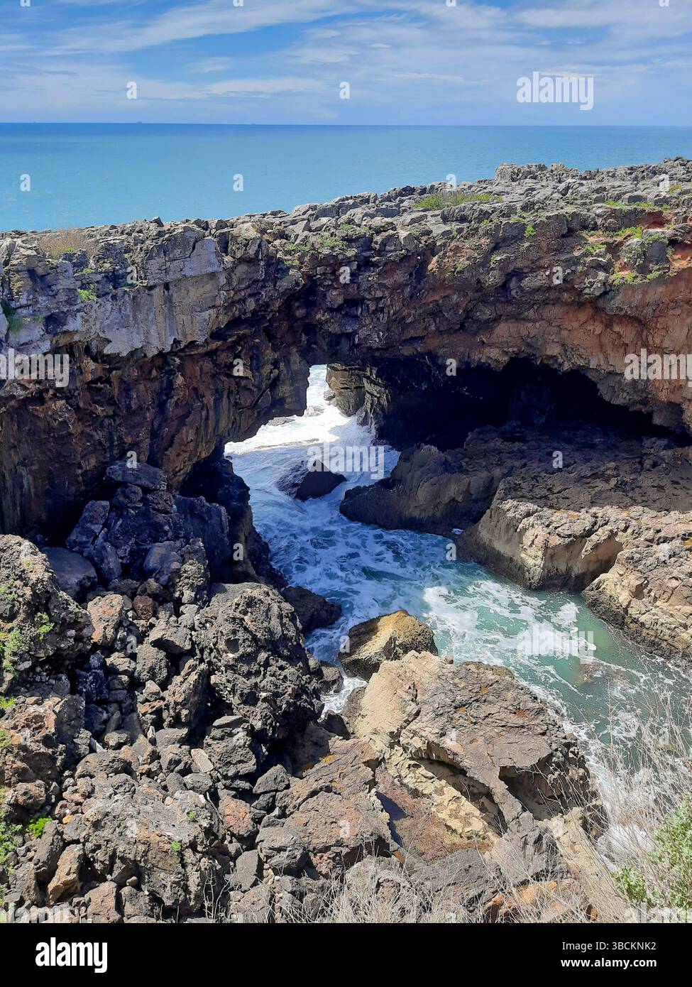 Striking natural rock arch and foamy waves at Boca do Inferno in ...