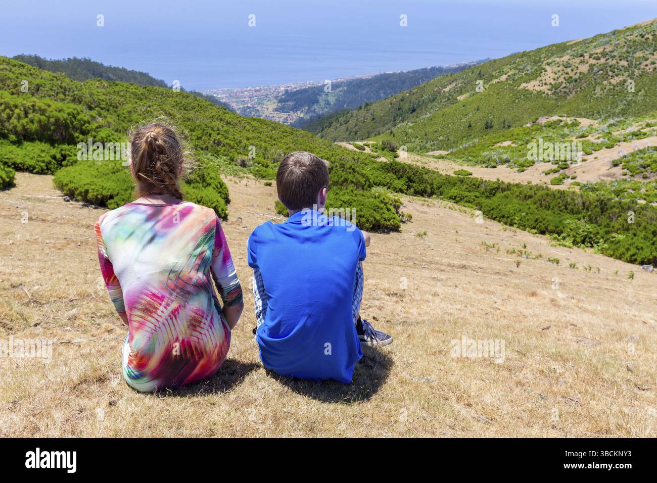 Dutch mother and son sitting in mountain landscape with valley and seaf ...