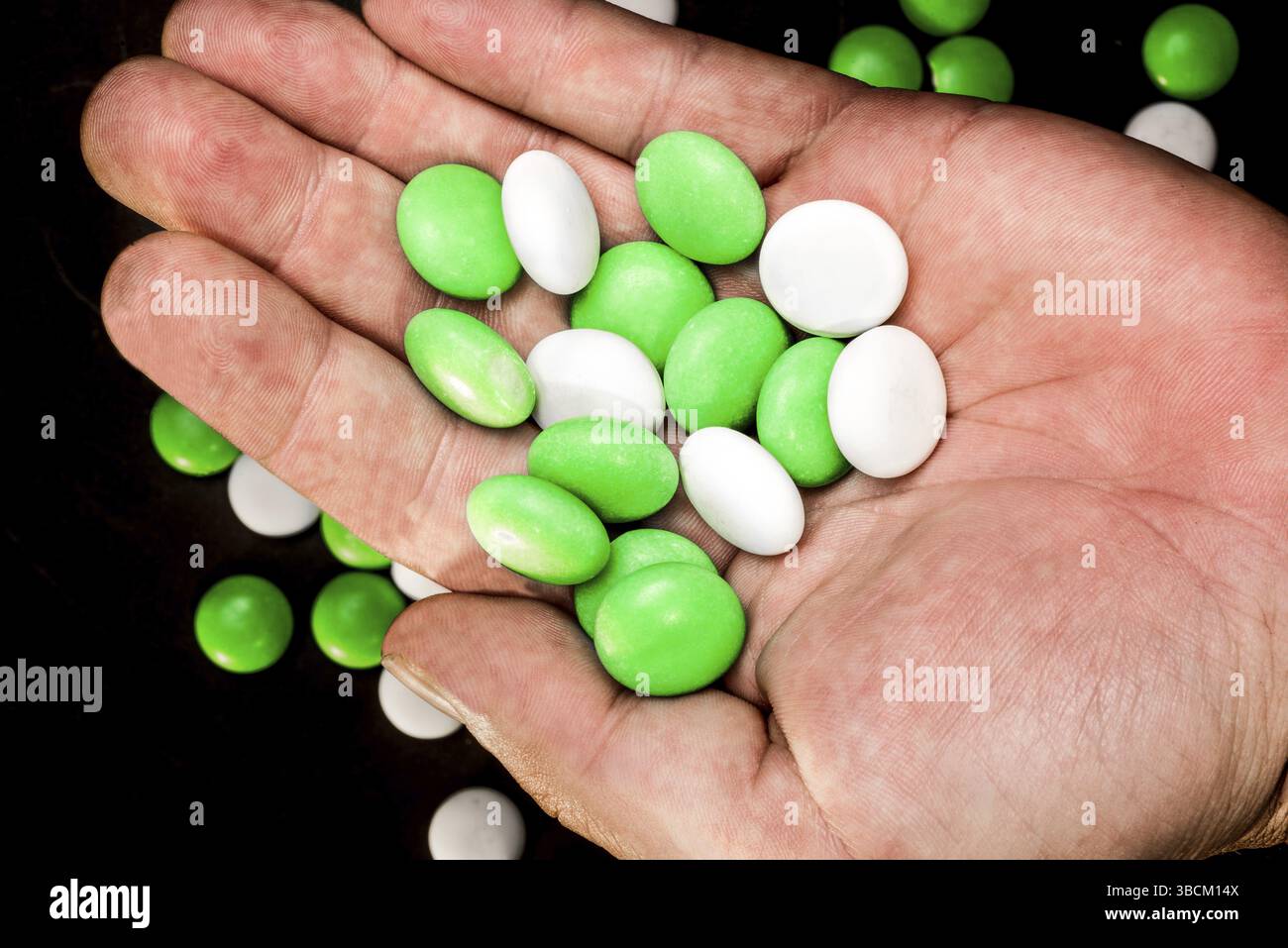 A hand holding several green and white mints in the palm while some ...