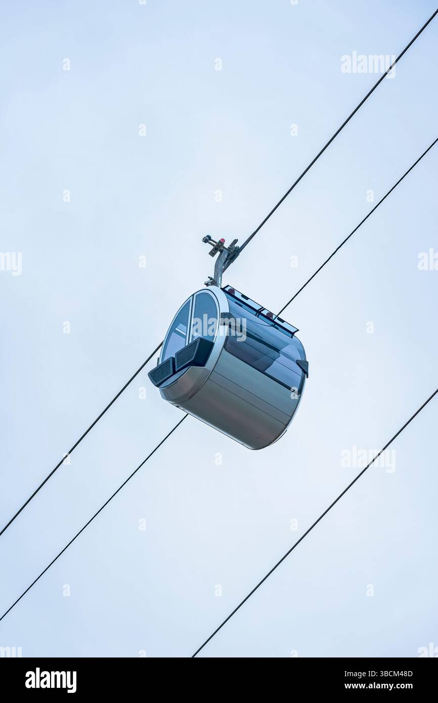 Modern cable car glides through sky on steel wires on soft cloudy ...