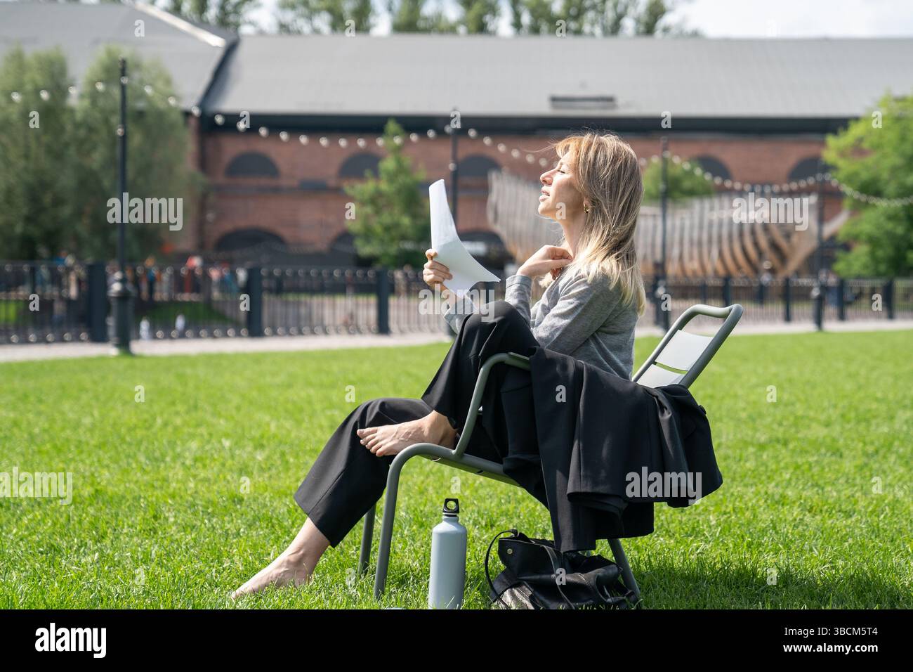 Uncomfortable woman fanning with sheets of paper like fan while sitting ...