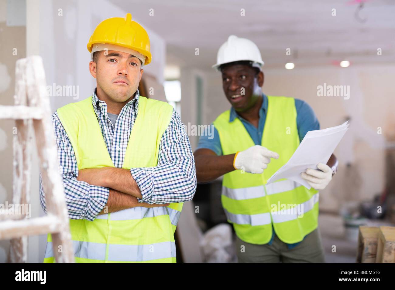 Portrait of confused man builder and angry foreman in construction site ...