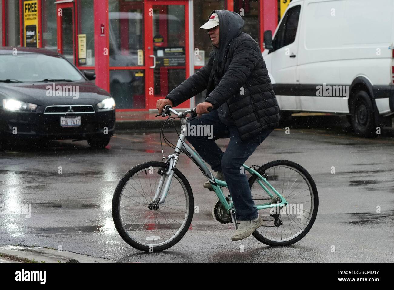 A commuter rides a bicycle during a rainy day in Wheeling, Ill ...
