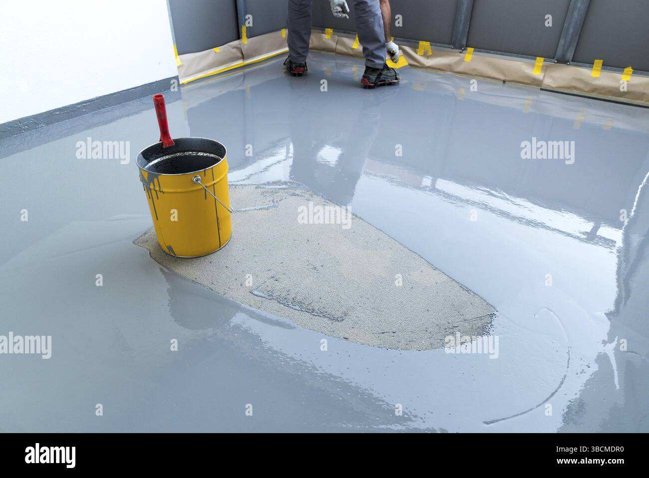 A construction worker renovates balcony floor and spreads watertight ...