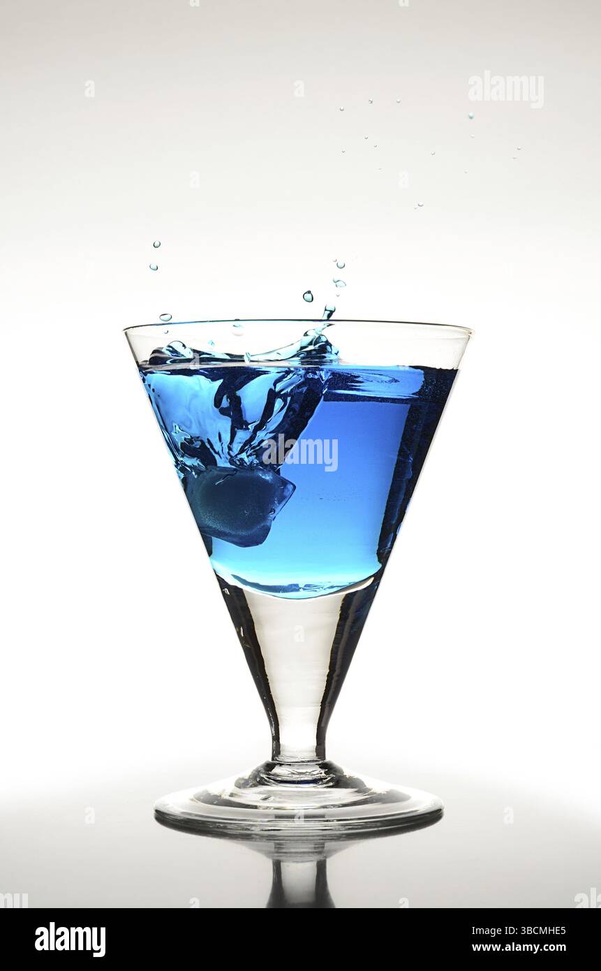 Blue cocktail with an ice cube and a big splash Stock Photo - Alamy