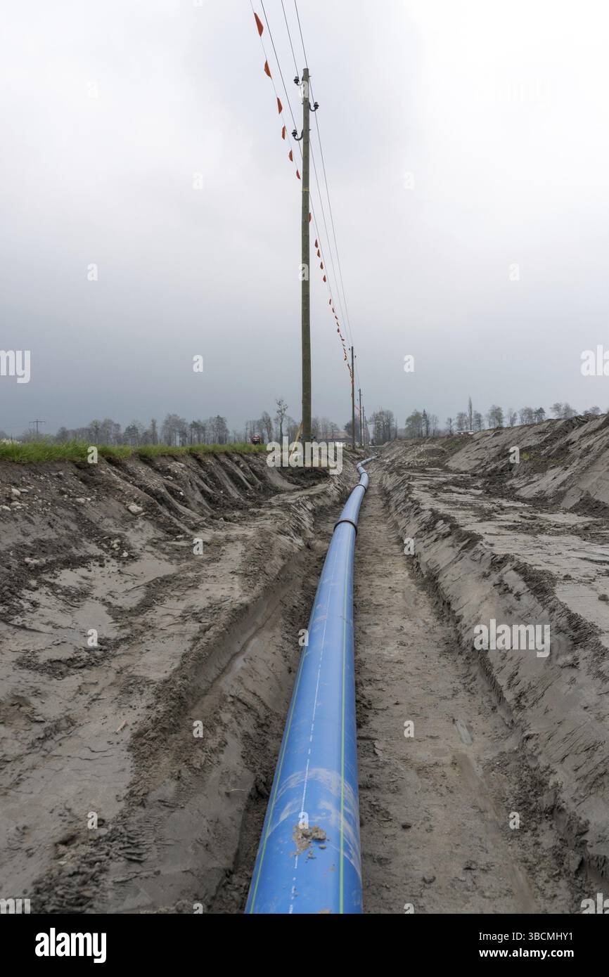 laying large industrial water pipes in an earth and dirt ditch for ...