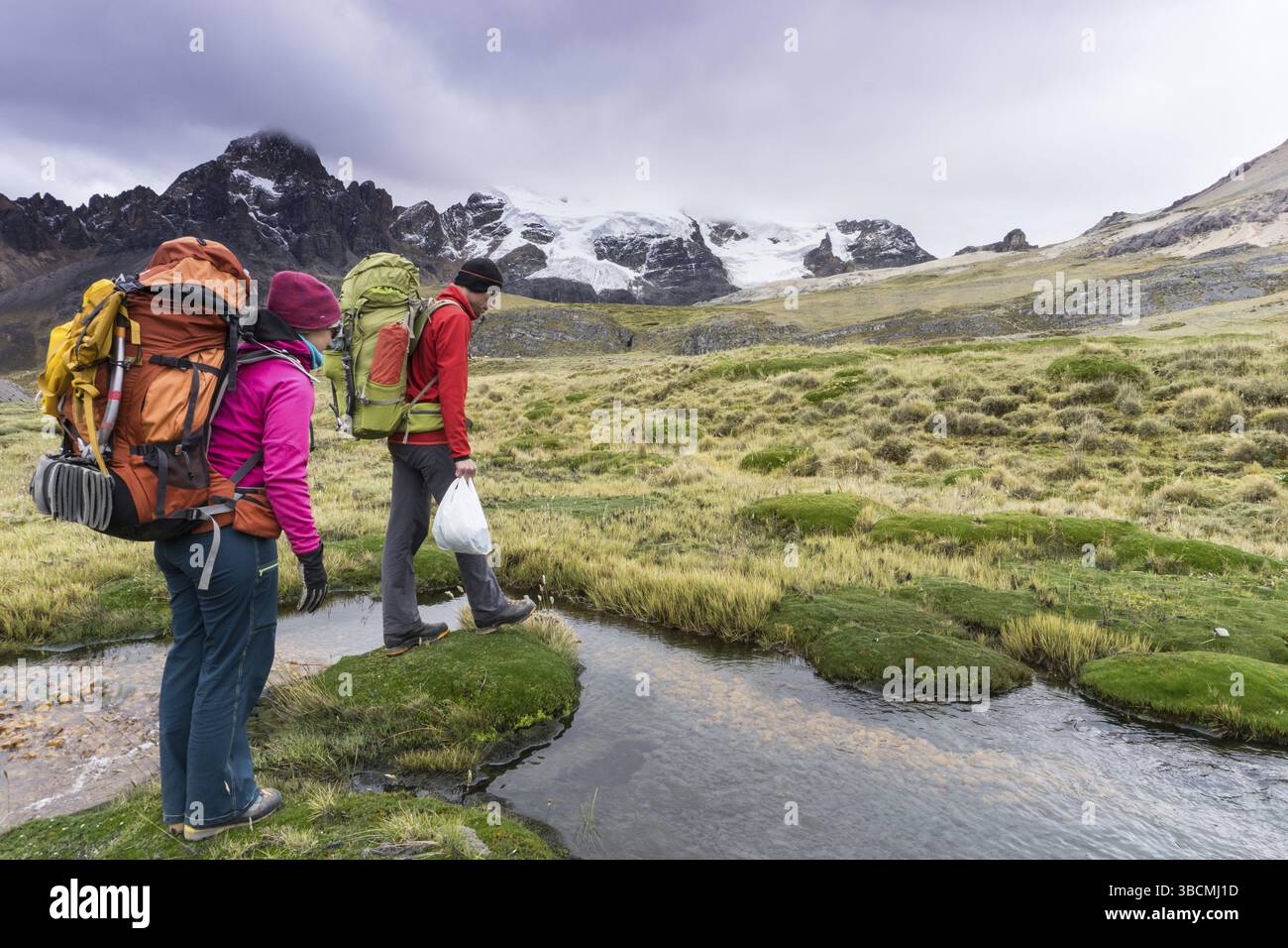 mountain climber couple crossing a small stream in the remote ...