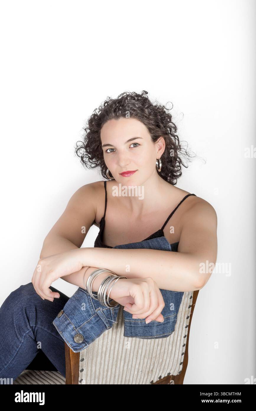 Young model in her mid twenties sitting on a chair with a blue denim ...
