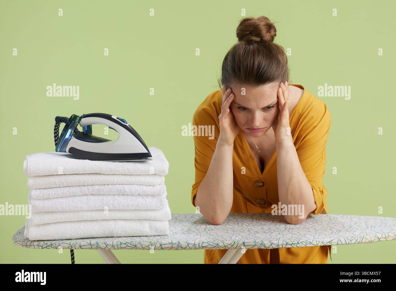 Frustrated woman in mustard dress holding her head in stress beside ...