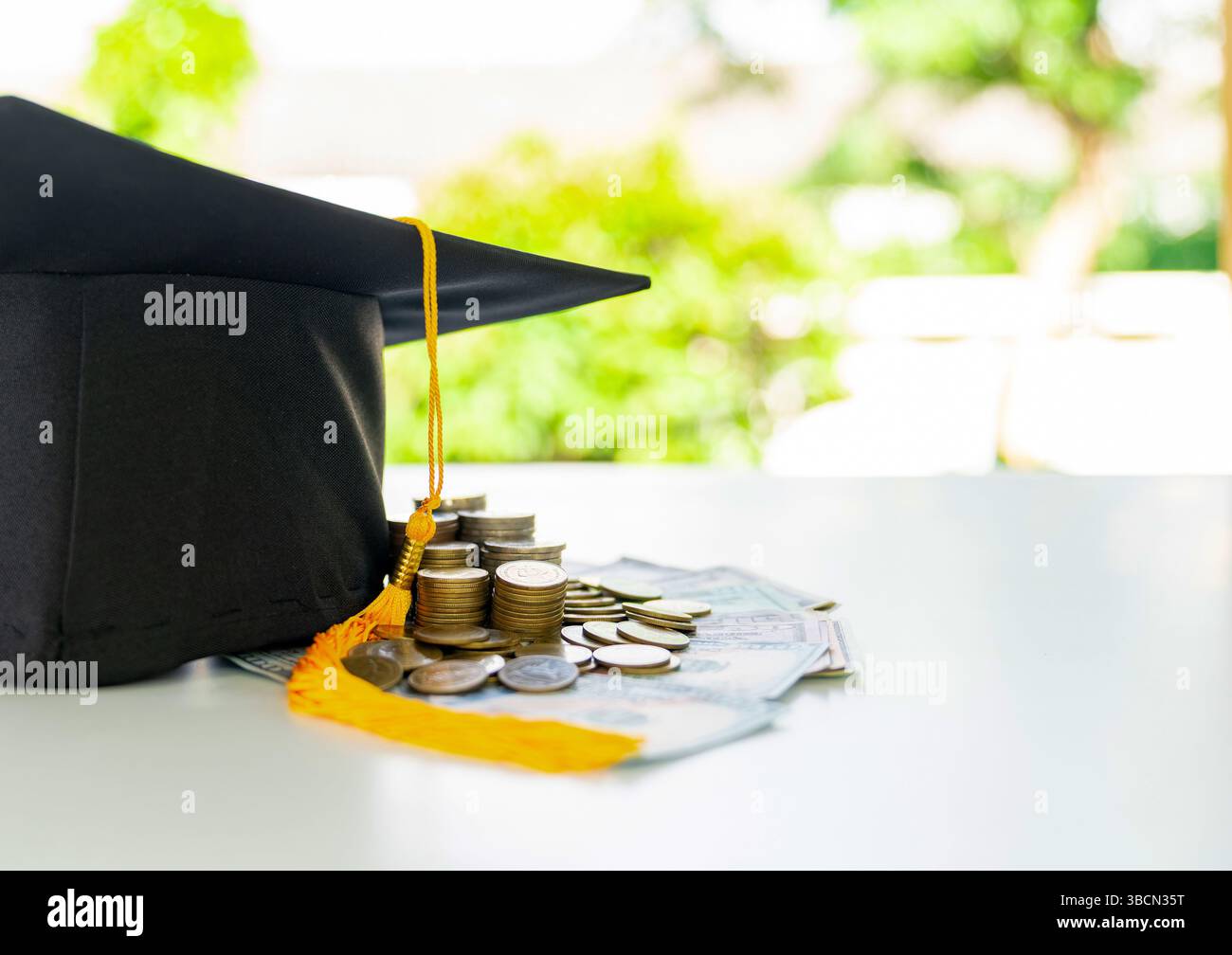 Graduation Cap on Stack of Coins and dollar bills on blur background ...