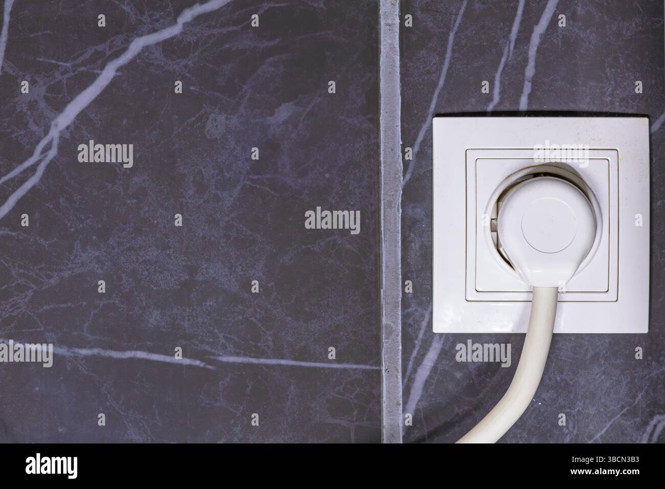 White corded plug is plugged into white power outlet on the black ...