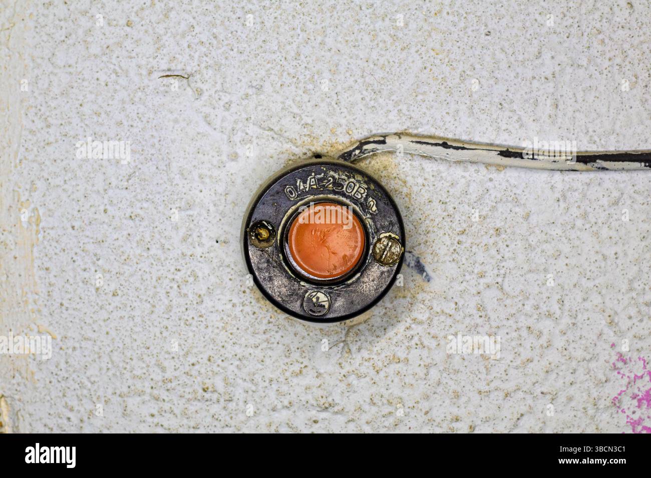 Old black round plastic doorbell with pink push button and black panted ...