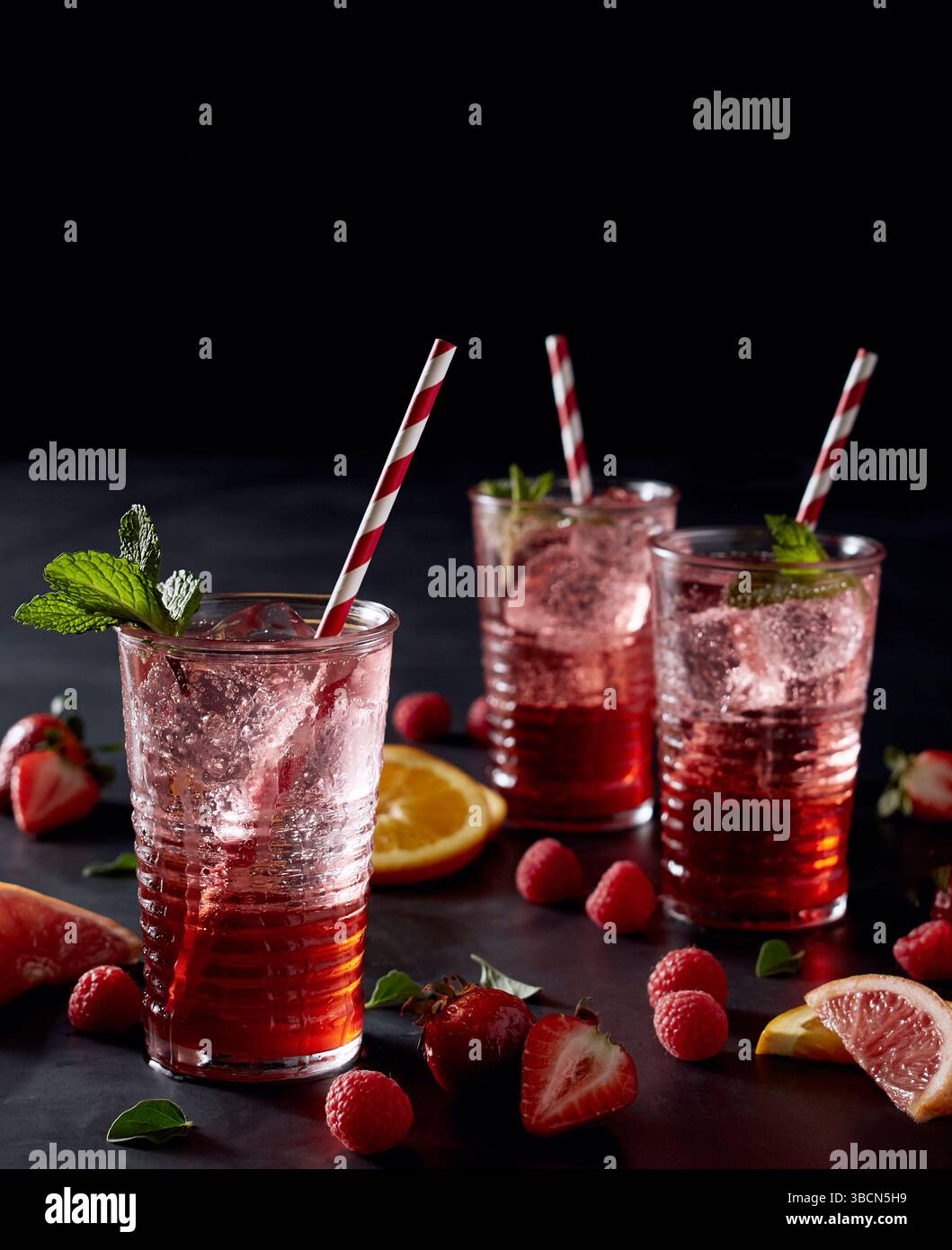 Berry cocktails with straws, citrus slices, and mint garnish Stock ...