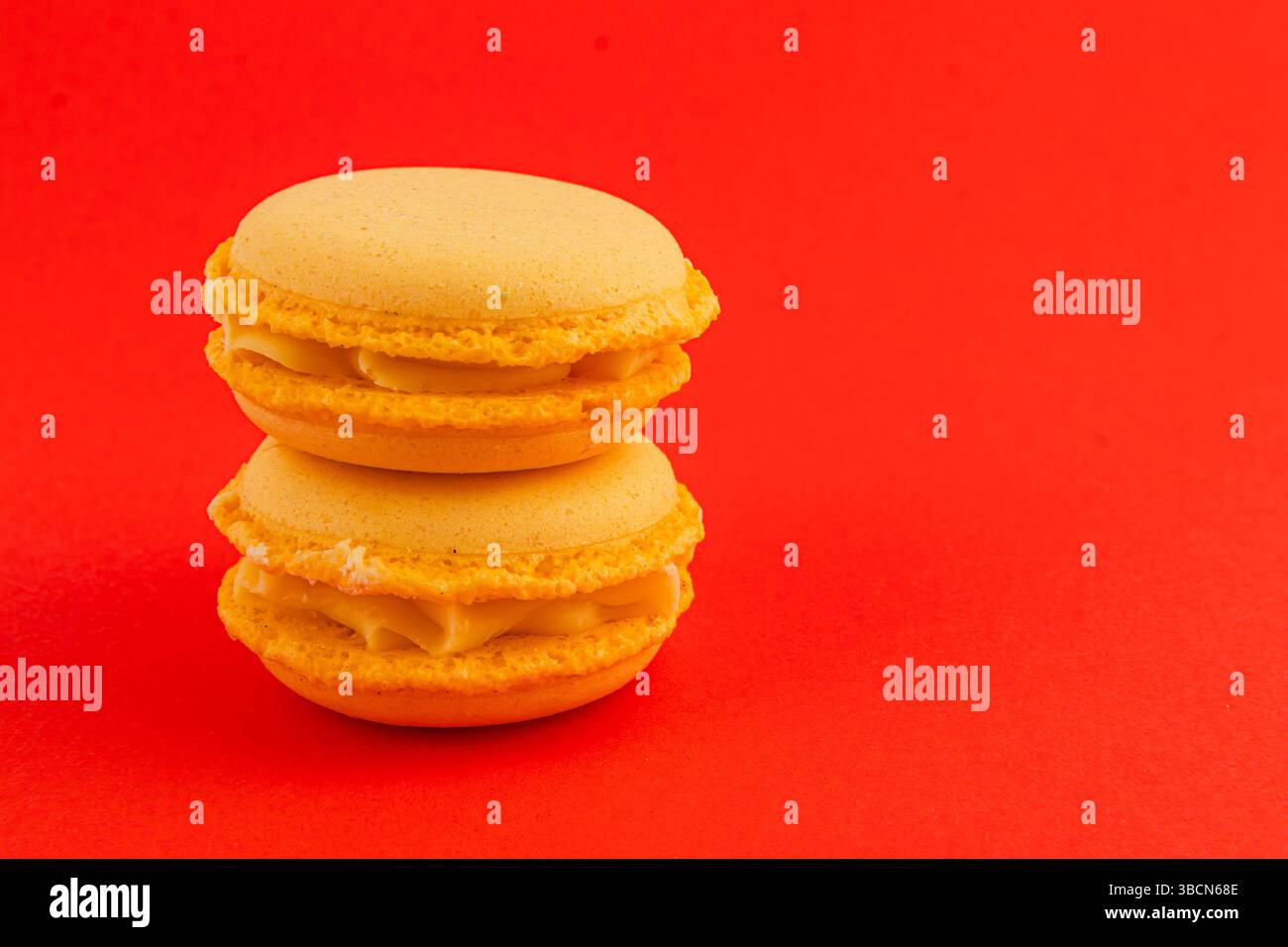 Two yellow macarons filled with cream are stacked on top of each other ...