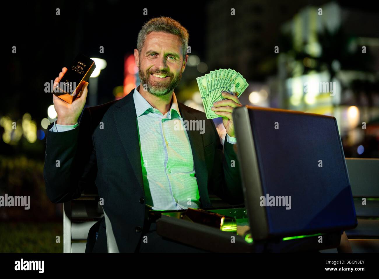 Rich man holding a gold bar. Businessman with stacks of money and gold ...