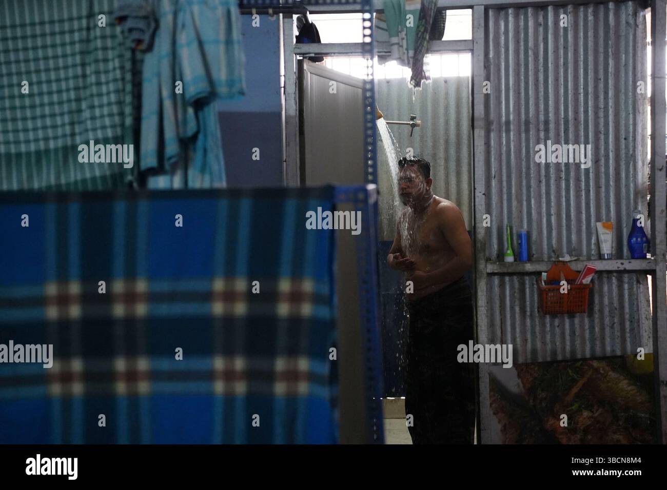 A Bangladeshi migrant worker takes a shower at his dormitory in Klang ...
