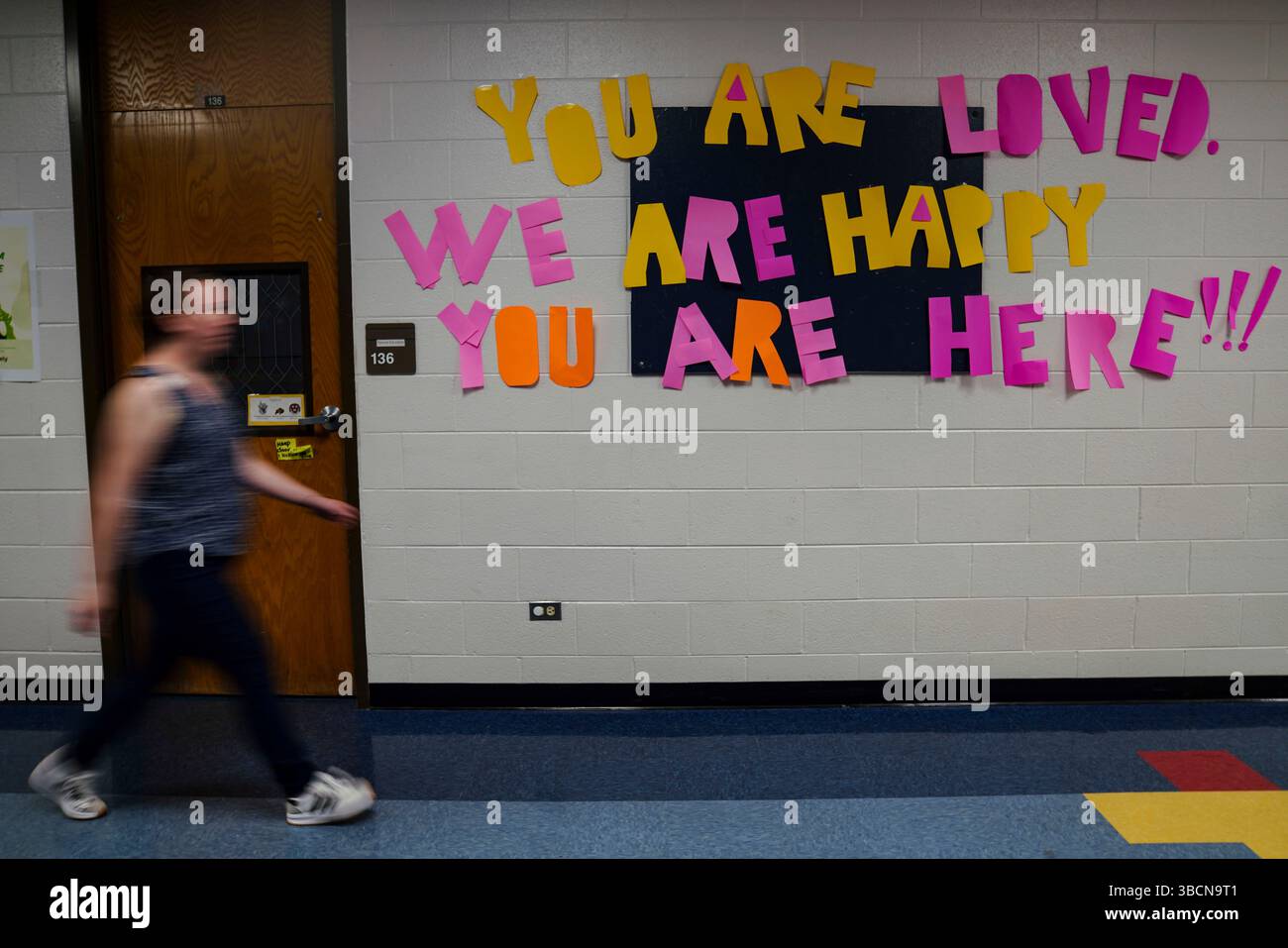 A staff member walks past a message to students that hangs on the wall ...
