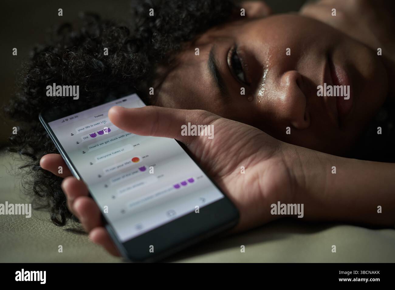 Close up portrait of crying black boy getting bullying messages in ...