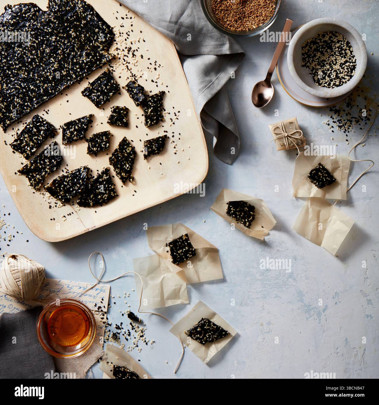 Sesame seed brittle pieces wrapped in parchment on textured surface ...