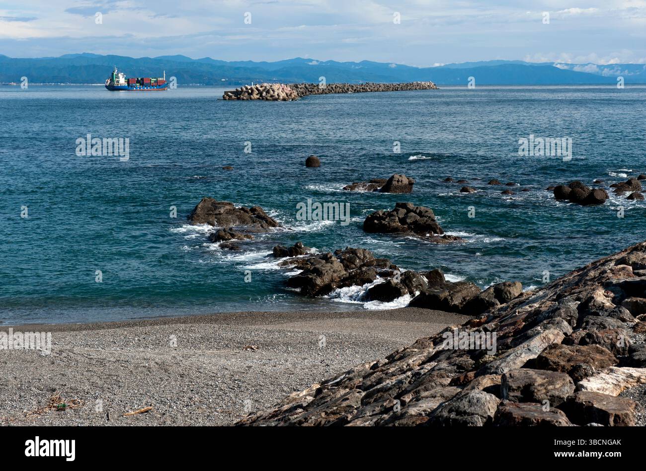 Scenic mountain and ocean view of a commercial ship heading out to sea ...