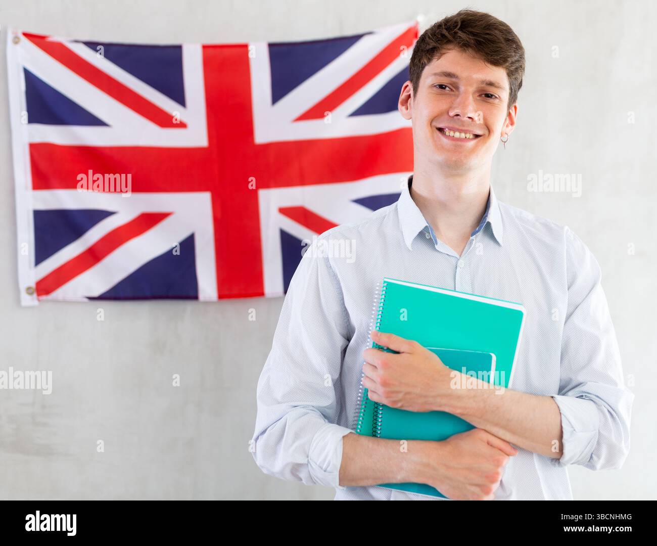 Male student with notebooks in his hands against background of the UK ...