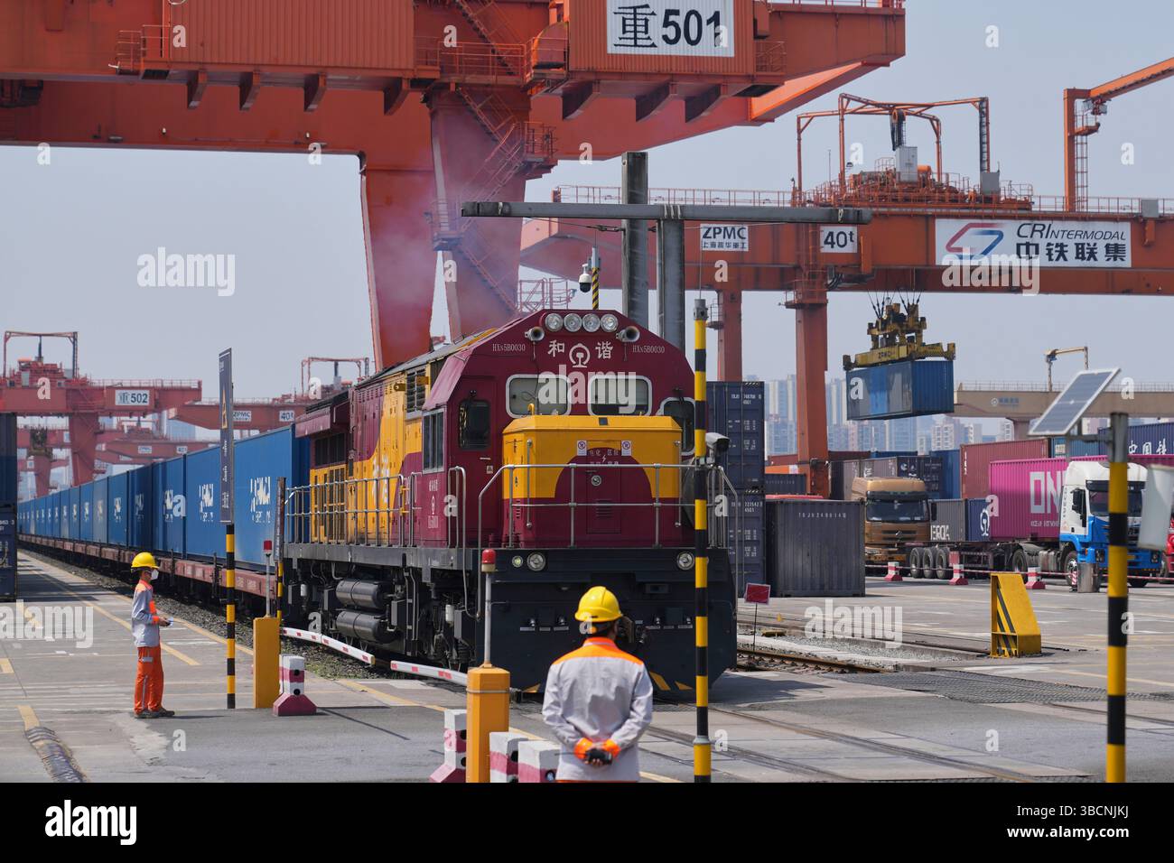 A worker stands watch as a train loaded with containers leave the ...