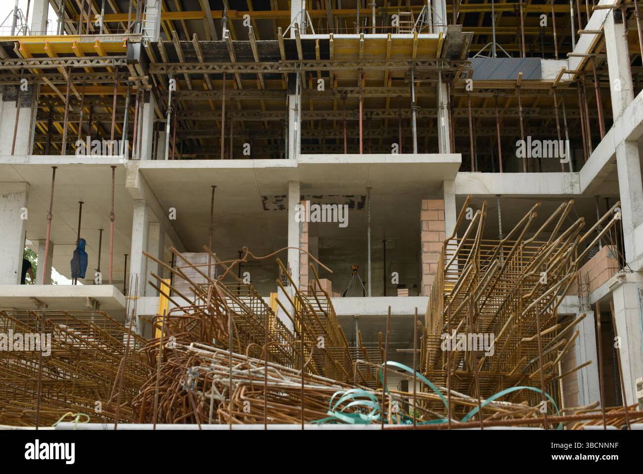 A reinforced concrete building frame at a construction site shows ...