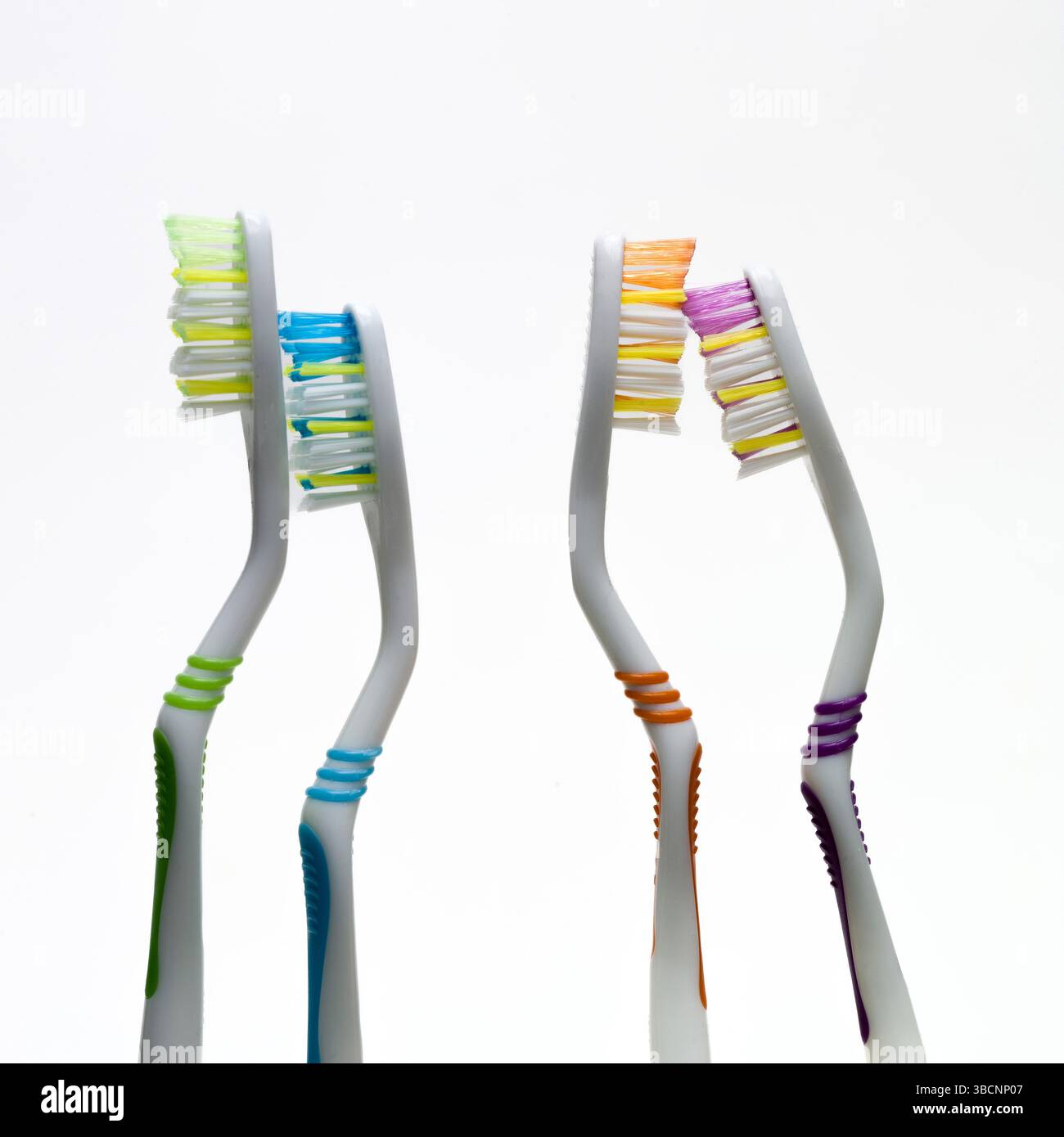 Four vibrant toothbrushes in varied colors stand side by side against a ...