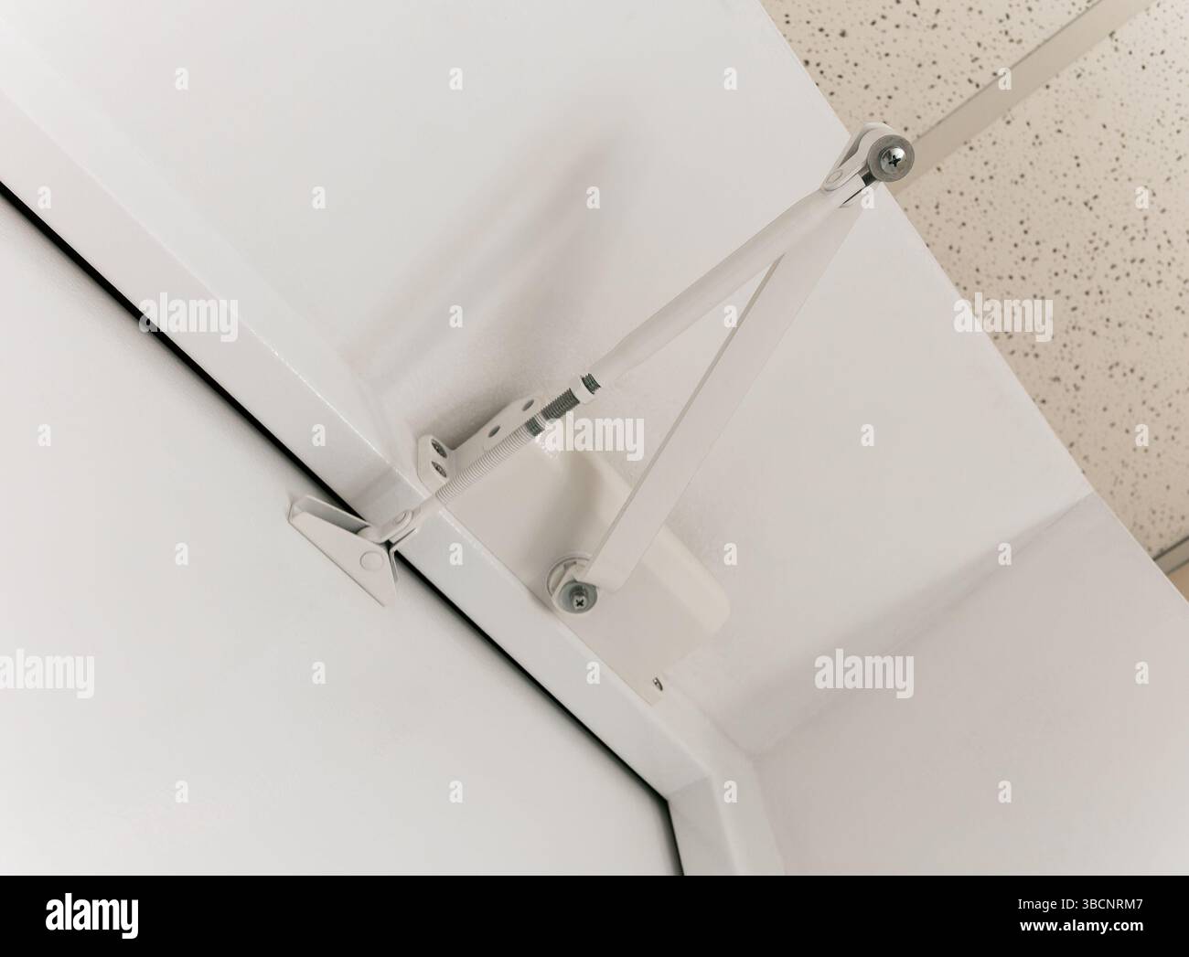 Bottom up view of a door closer installed on a metal white door Stock ...