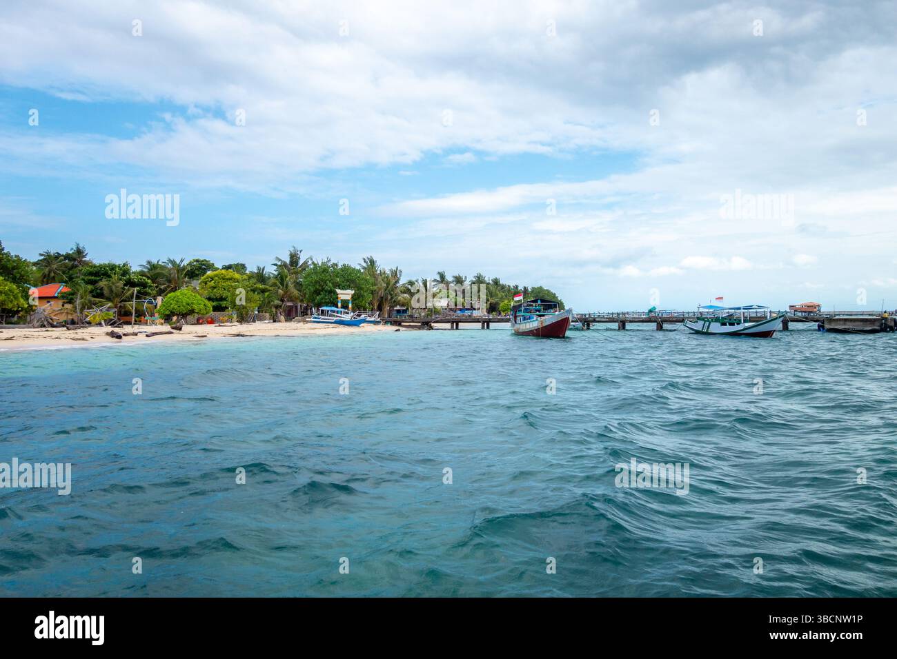 Colorful fishing boats dock along the sandy shore of Pulau Liukang Loe ...