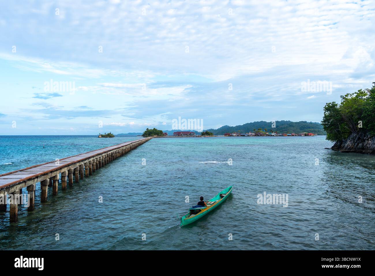 A long wooden jetty stretches over turquoise waters towards the ...