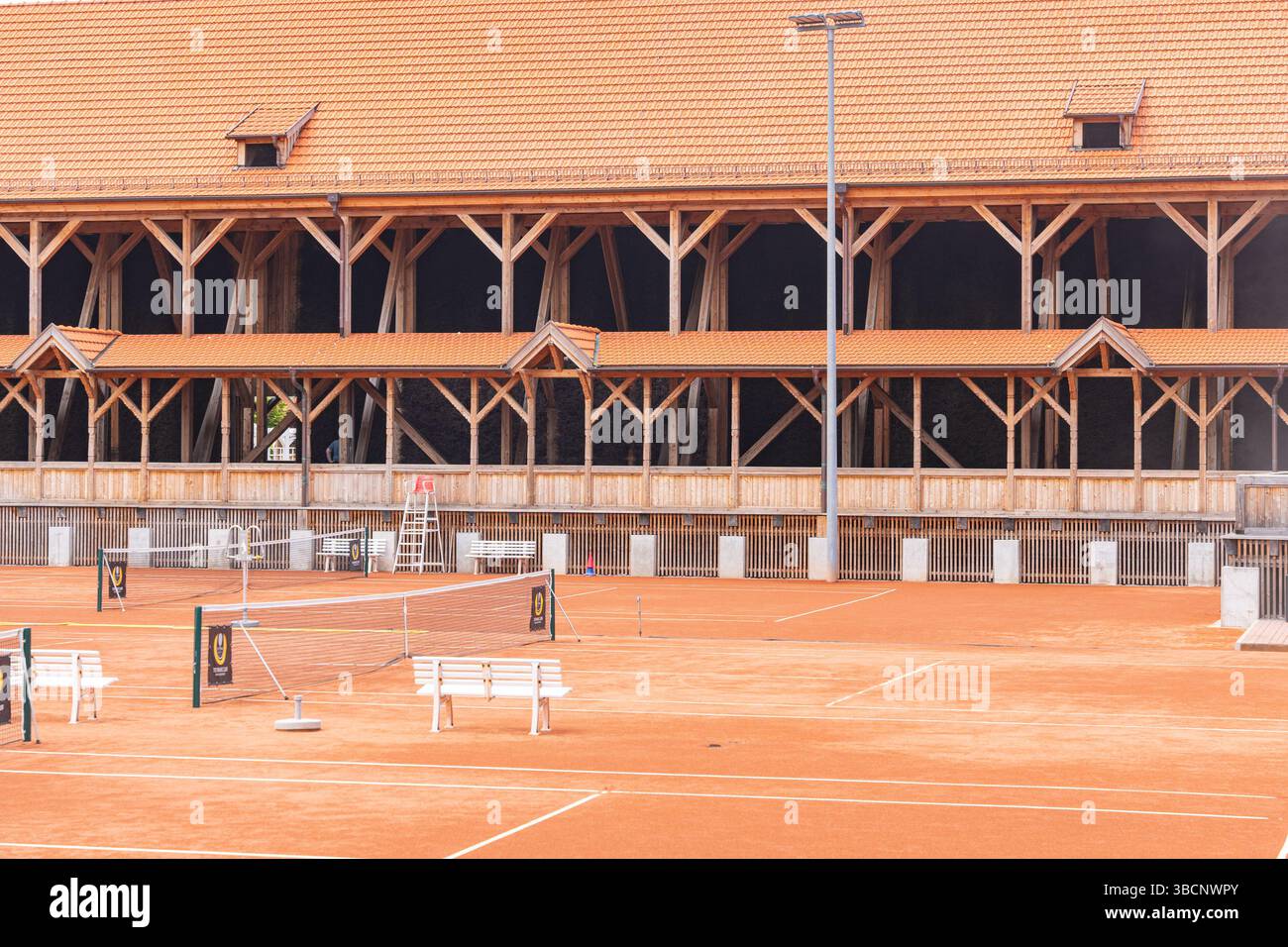 An outdoor clay tennis court is set against the backdrop of a large ...