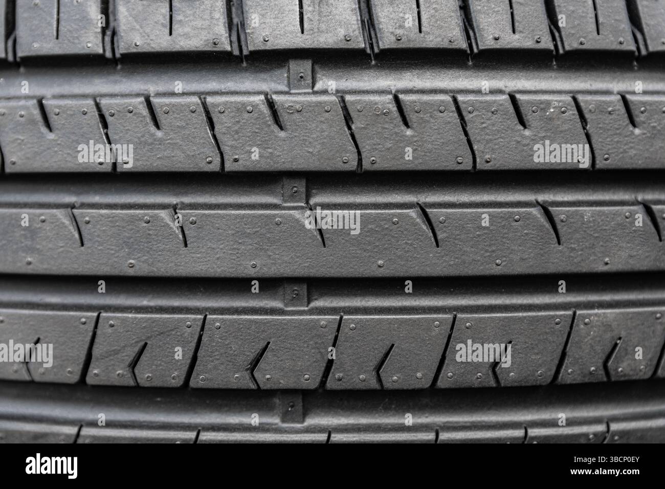 Detailed close-up of a black rubber tire tread pattern, showing texture ...