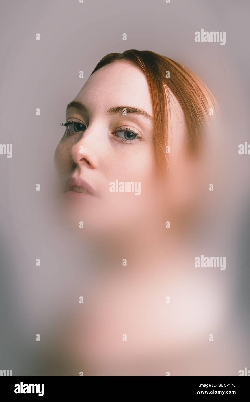 Surreal collage. Red-haired woman looks sideways with piercing eyes ...