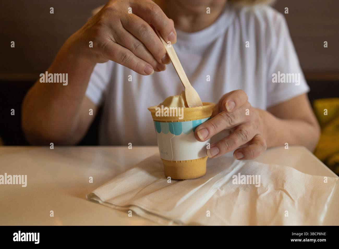 Senior woman eating ice cream with wooden spoon, eco-friendly ...