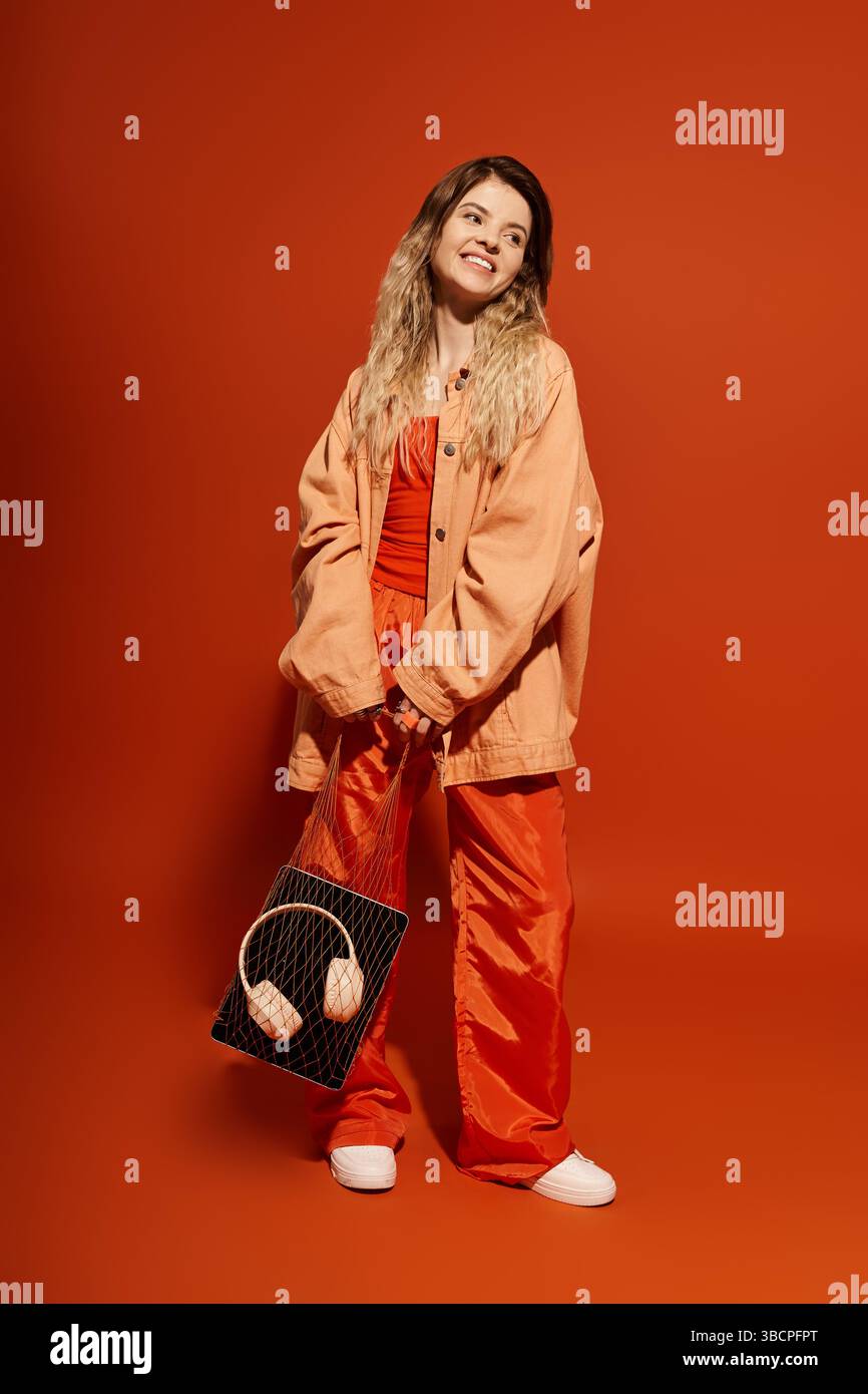 Pretty young woman radiates joy in her stunning orange outfit against a ...