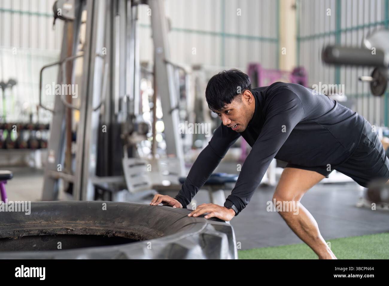 Tire Push Workout. A man pushing a heavy tire for strength and ...
