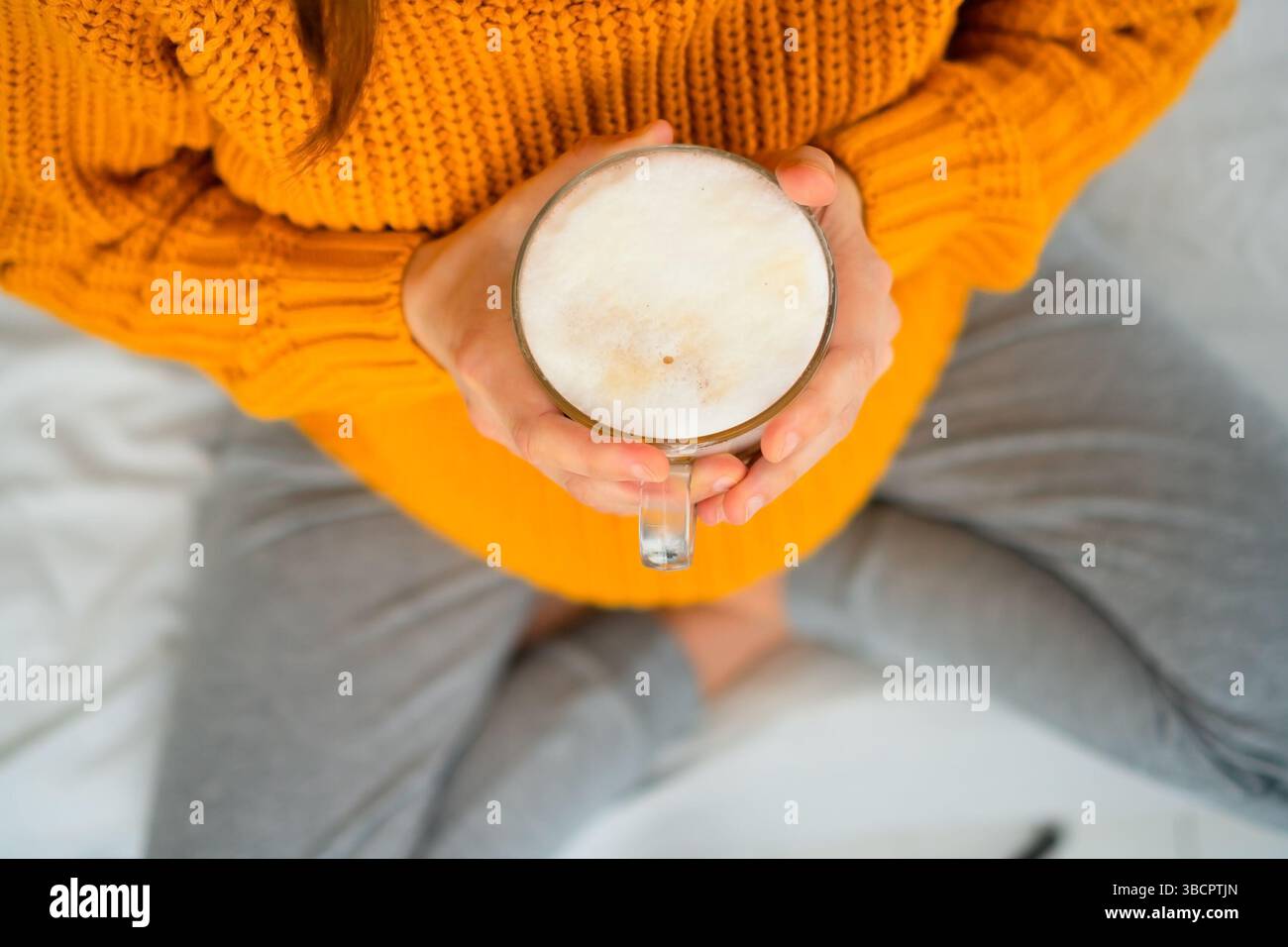 Close overhead shot shows expecting mother holding latte while ...