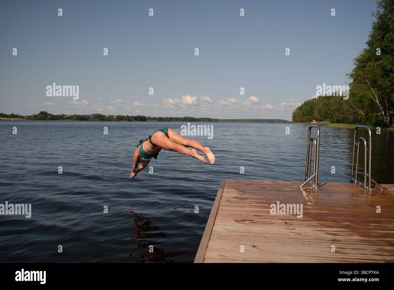 Fit woman diving headfirst from pier into lake. Healthy body, strong ...