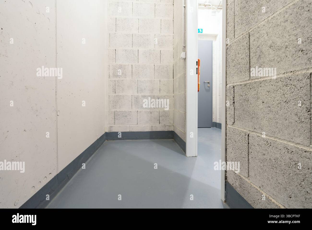 Small utility storage room with concrete walls and exit door in modern ...
