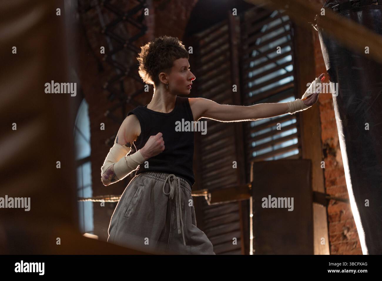 Female boxer training in cinematic gym lighting, powerful punch on bag ...