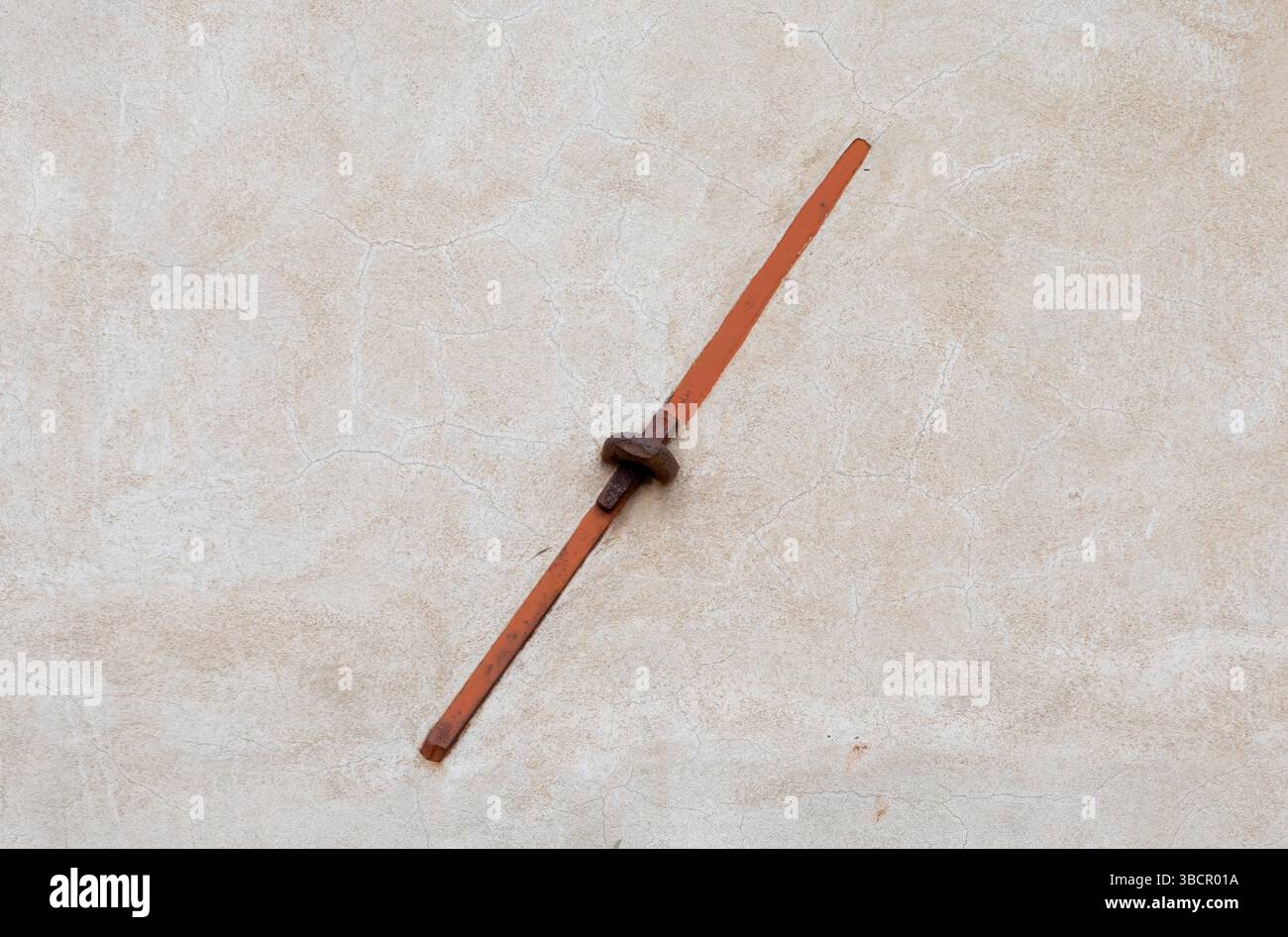 Close up of a metal tie rod, painted in orange, attached to a cracked ...