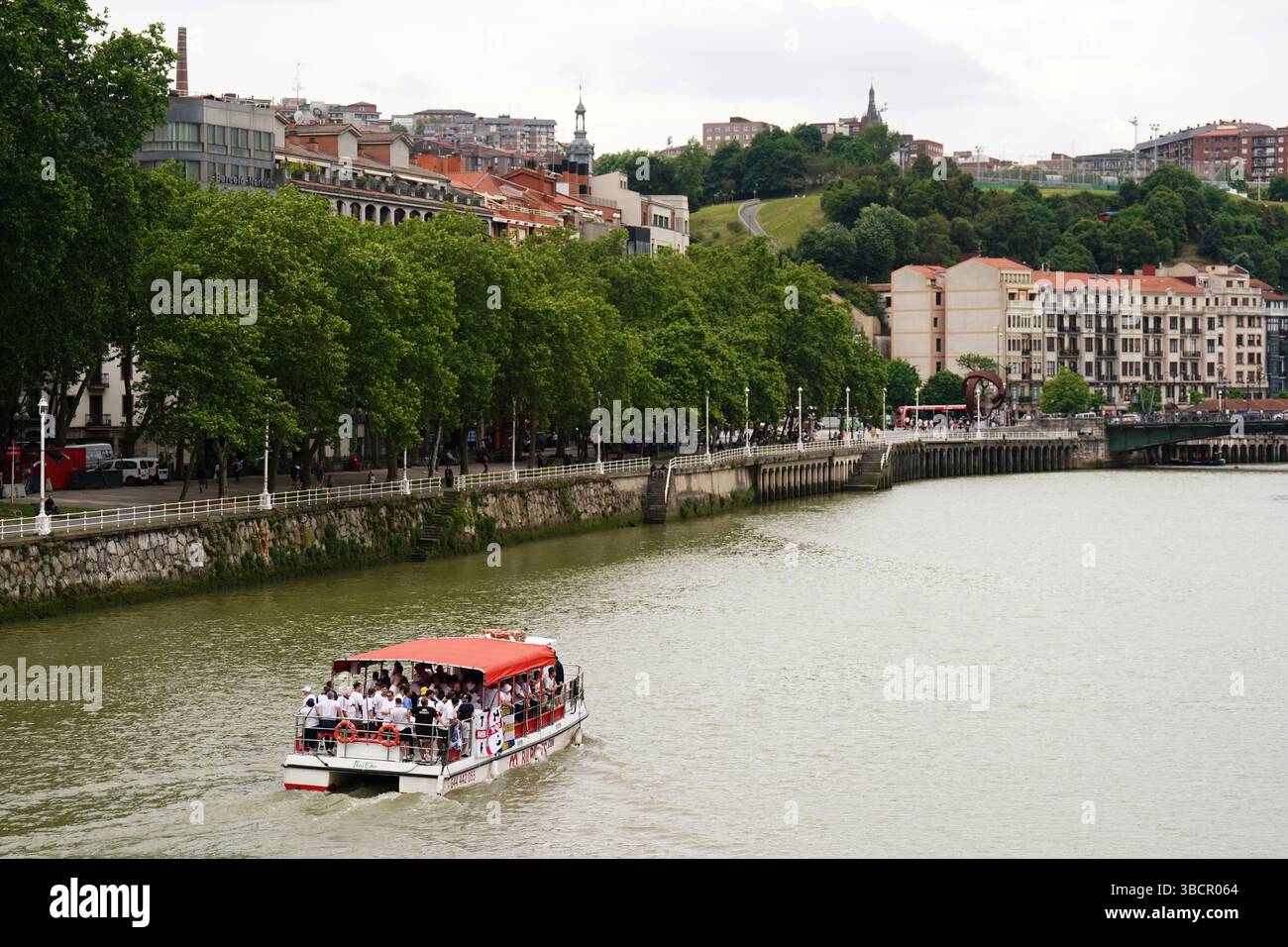 A boat full of Tottenham Hotspur fans heads down the Nervion River in ...