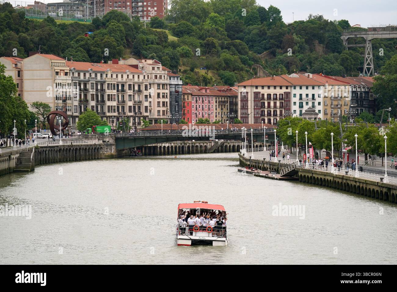 A boat full of Tottenham Hotspur fans heads down the Nervion River in ...