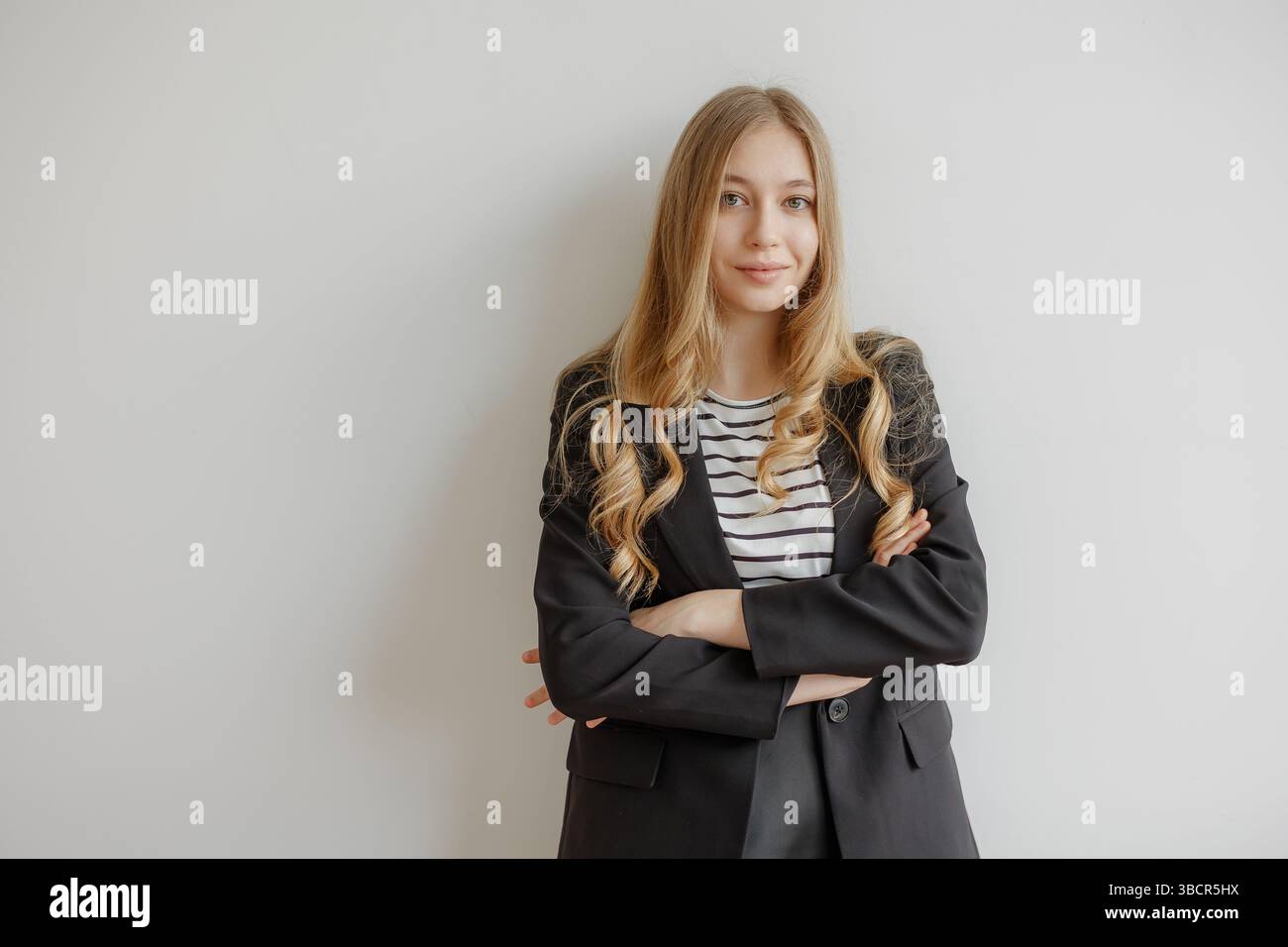 Professional woman poses confidently with crossed arms against a plain ...
