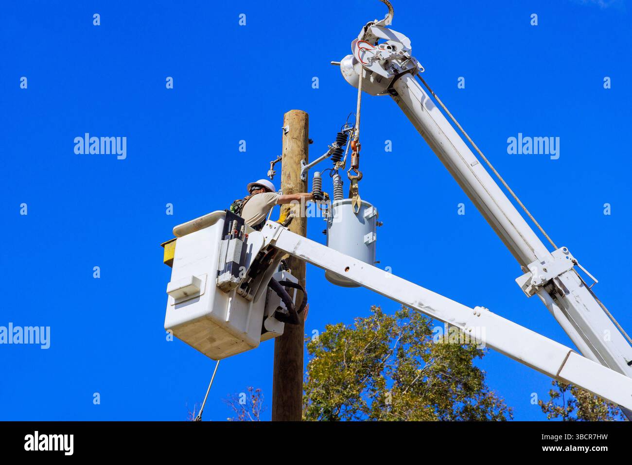 Utility worker is repairing equipment on power lines from lift truck ...